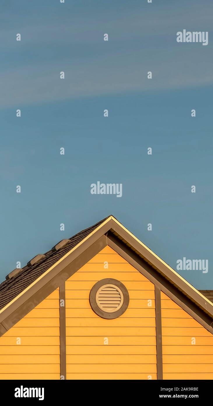 Vertical frame House exterior with roof shingles and round gable window ...