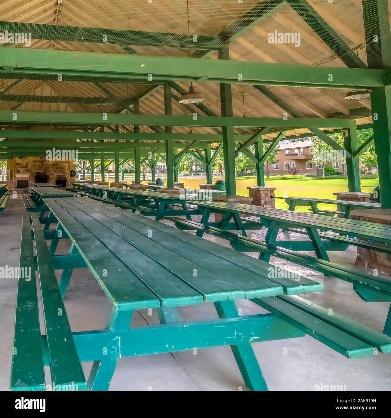 Square Pavilion at a park with tables and seats under roof with green ...