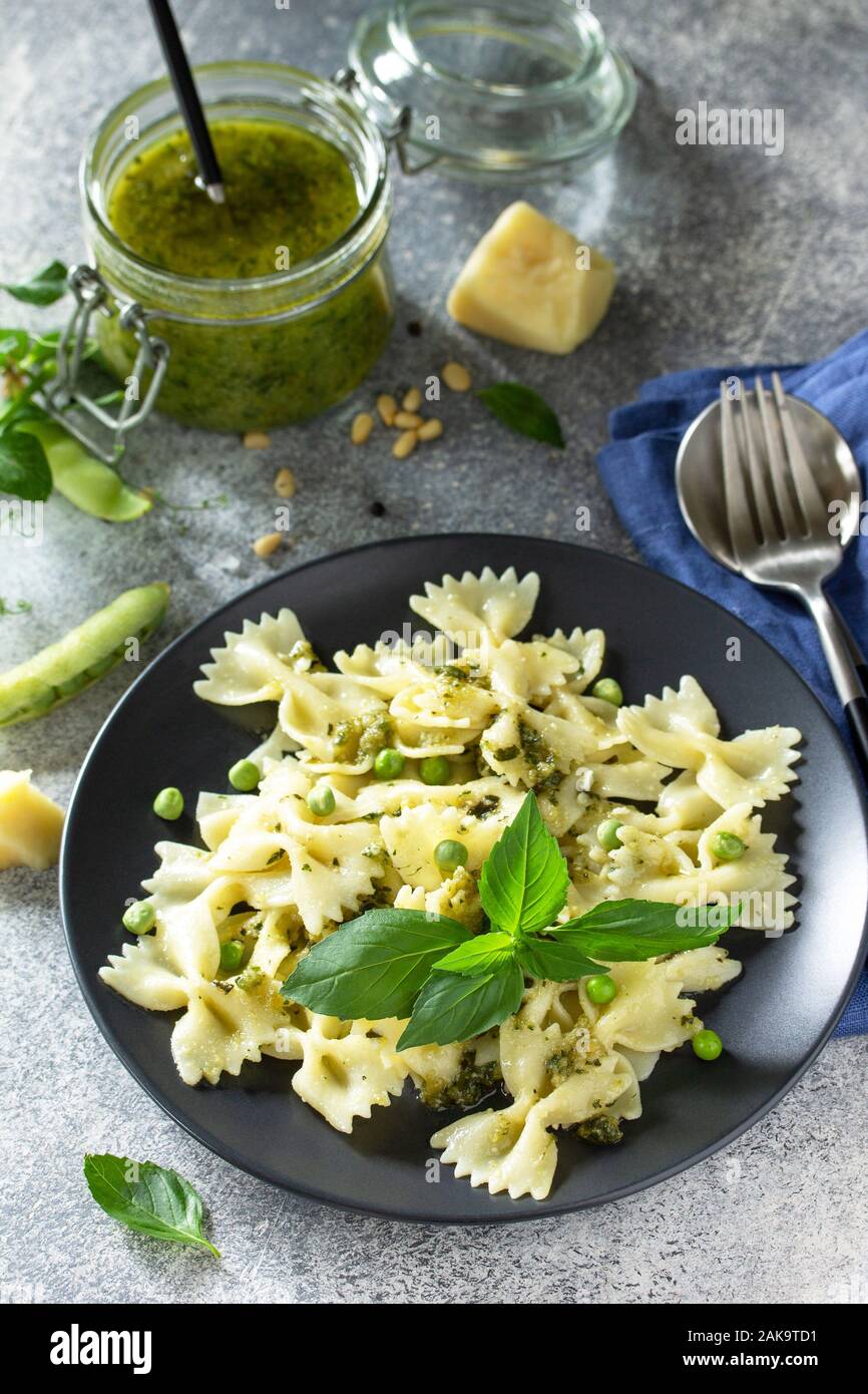 Healthy Italian cuisine. Pasta with green peas and pesto sauce in black ...