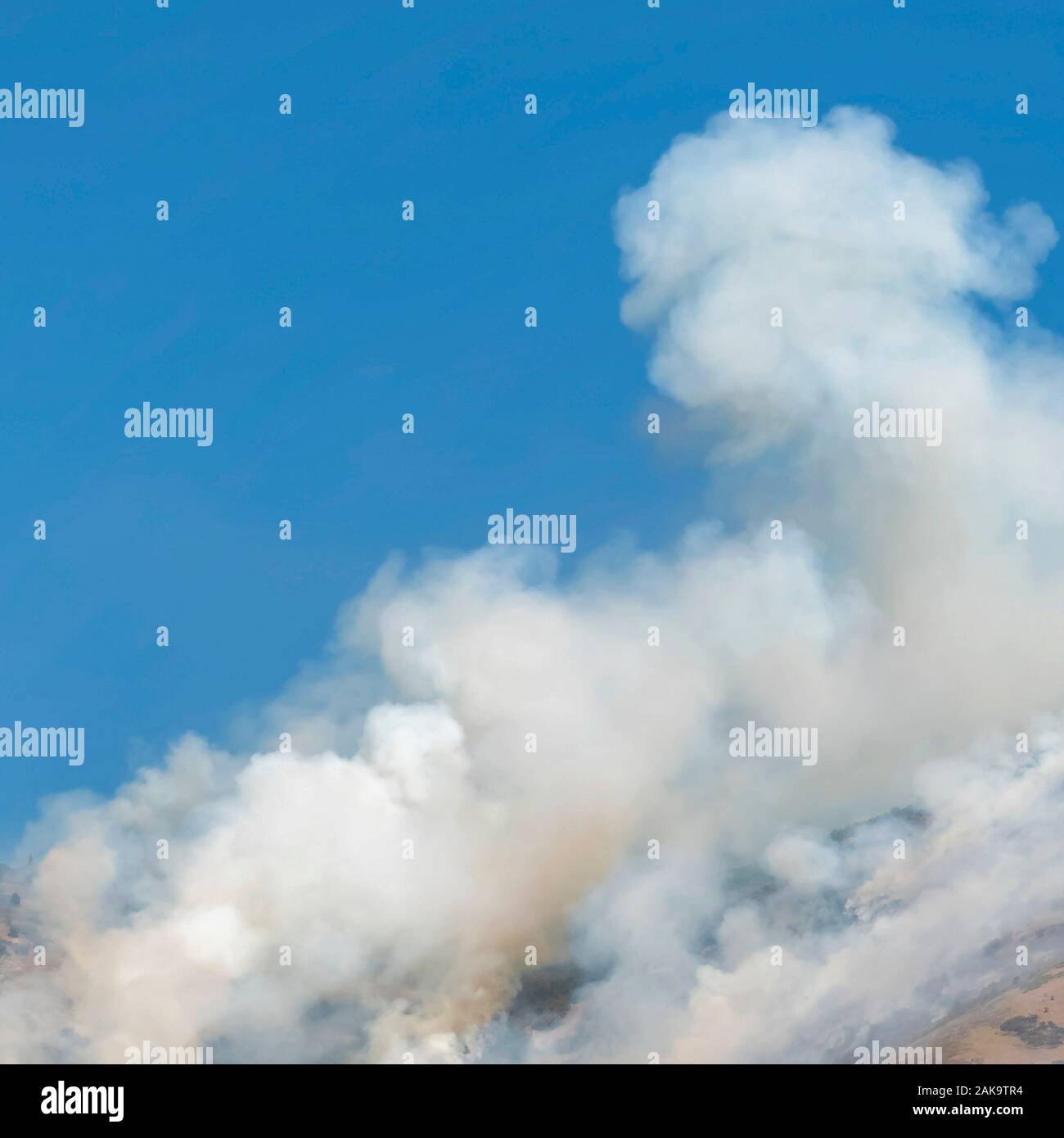 Square Thick puffs of smoke from fire in the mountain against clear ...