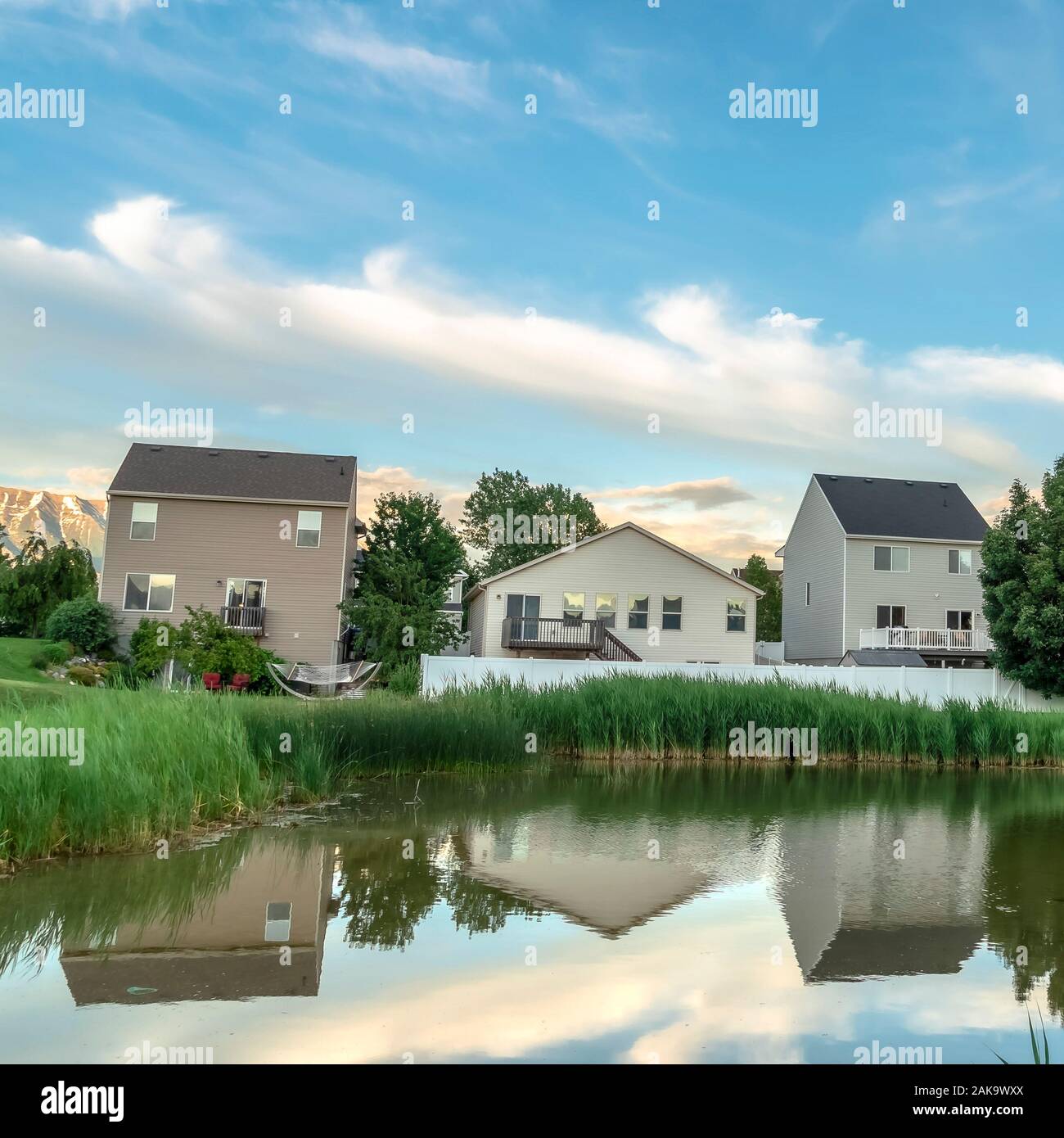 Square Scenic suburban landscape with homes and cloudy sky reflected on ...