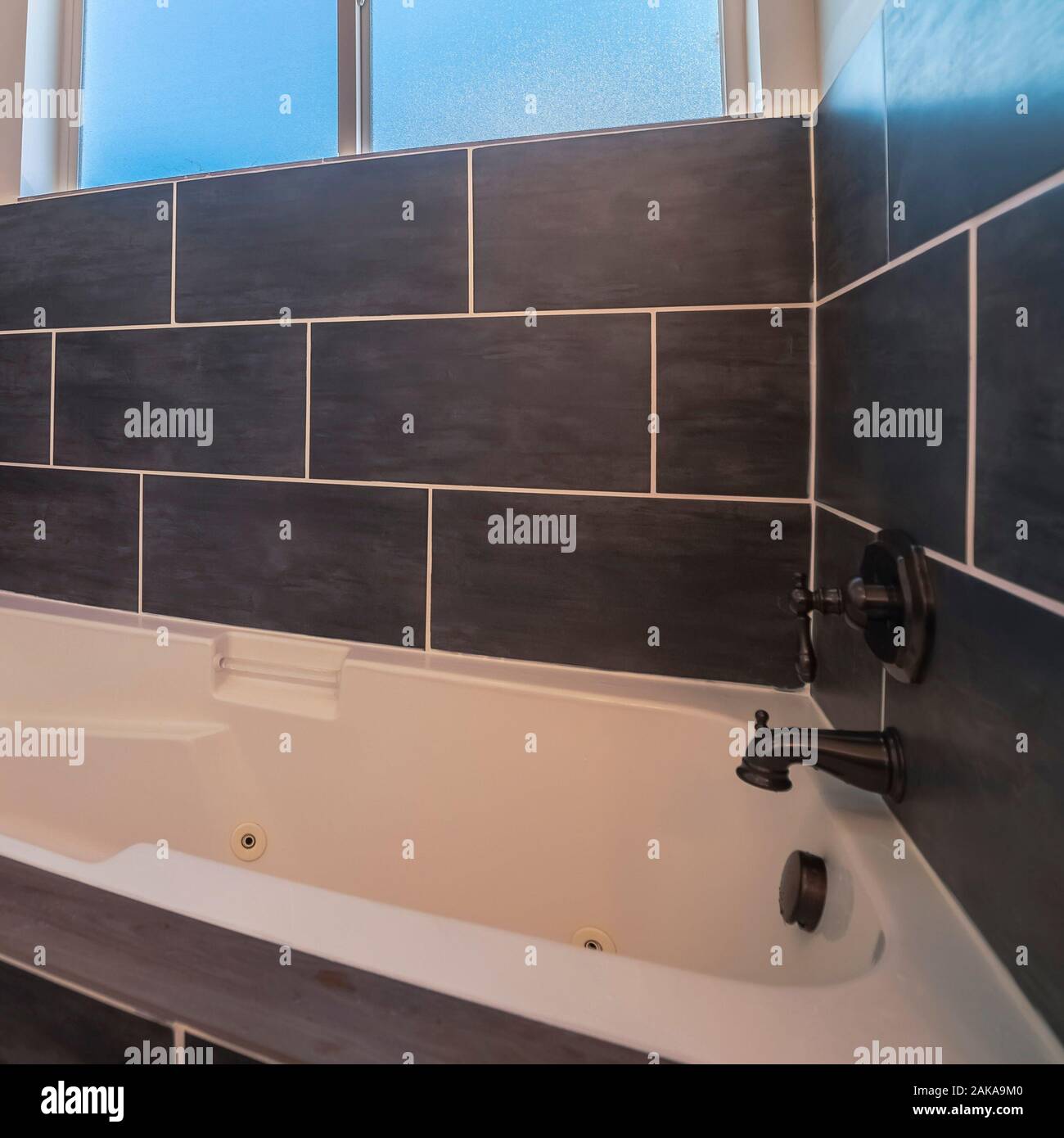 Square Small fitted tiled bathtub in a modern bathroom Stock Photo - Alamy