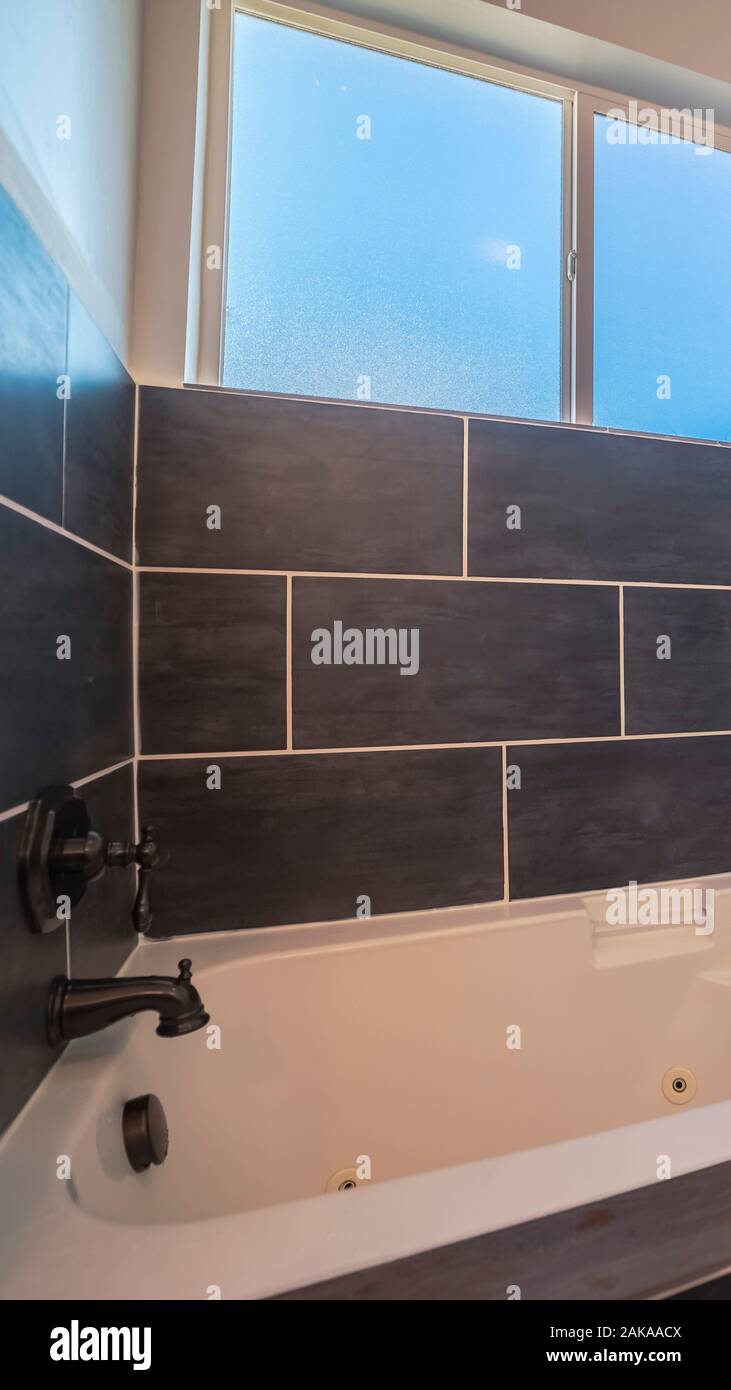 Vertical Small fitted tiled bathtub in a modern bathroom Stock Photo ...