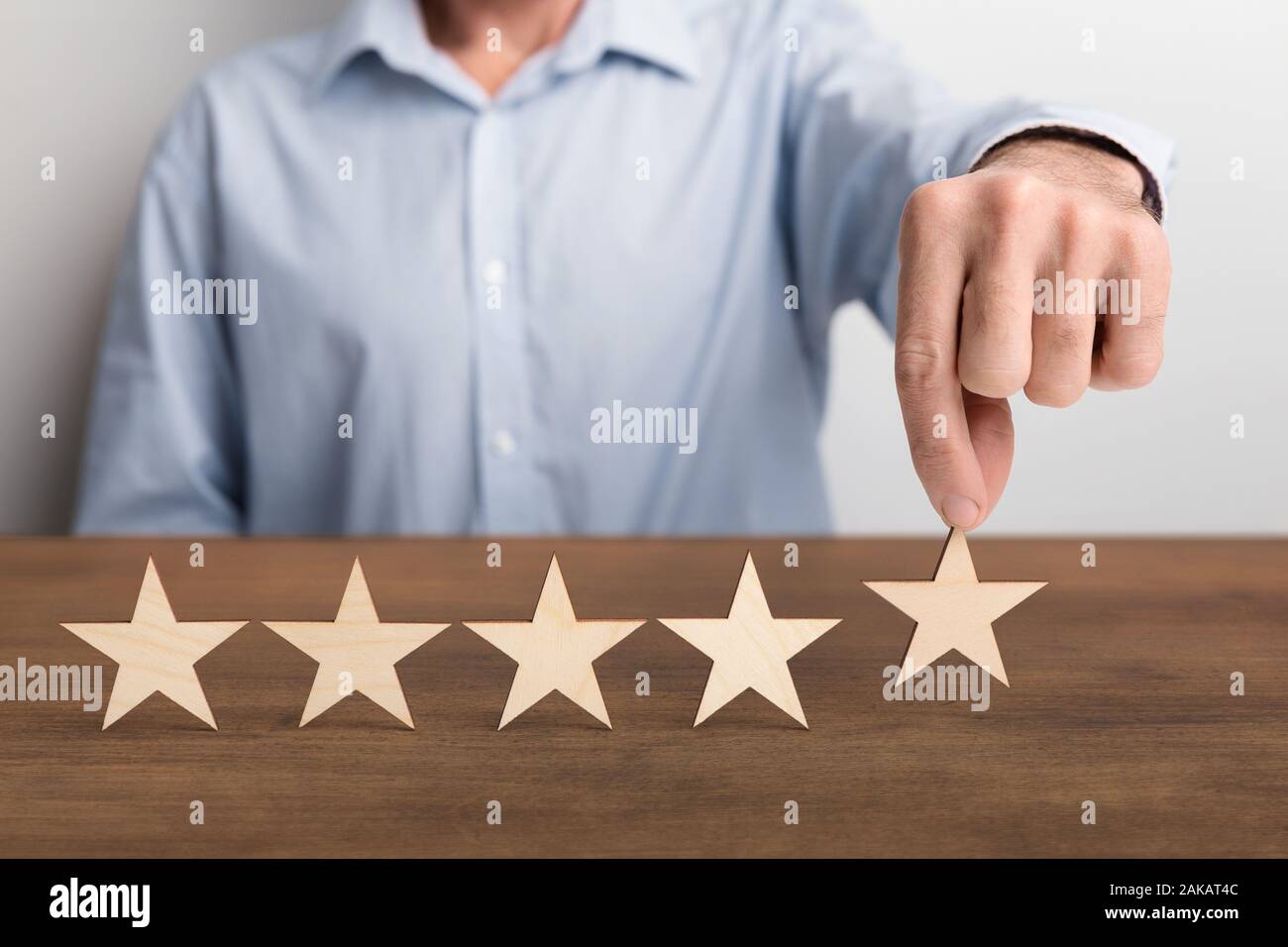 Man Hand putting wooden five star blocks on table. The best excellent ...