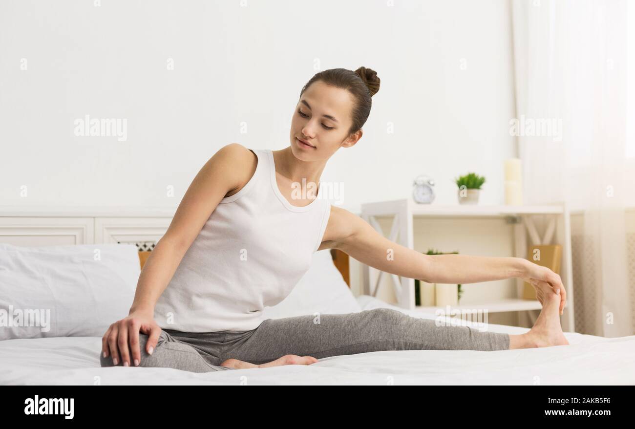 Healthy lifestyle. Young woman doing morning stretching on bed, routine ...