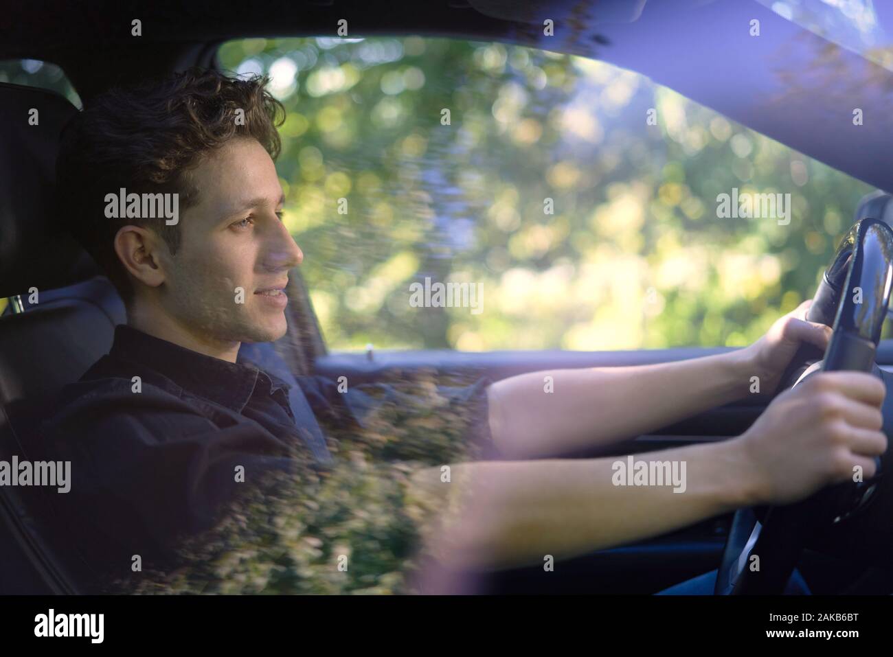 Portrait of a young handsome man driving his car with both hands at the ...