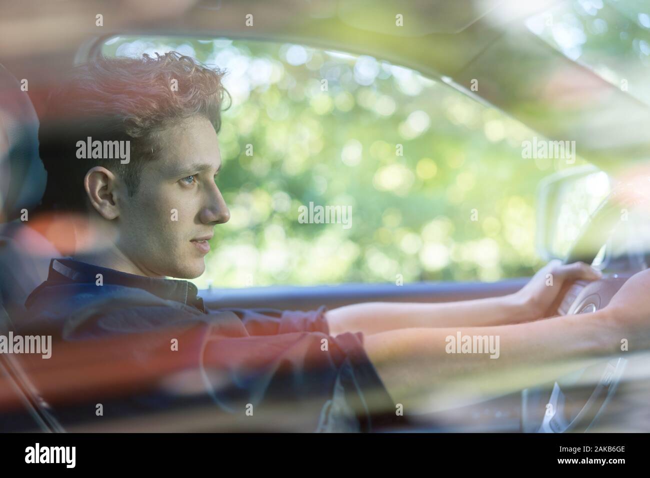 Young relaxed driver with hands at the wheel Stock Photo - Alamy