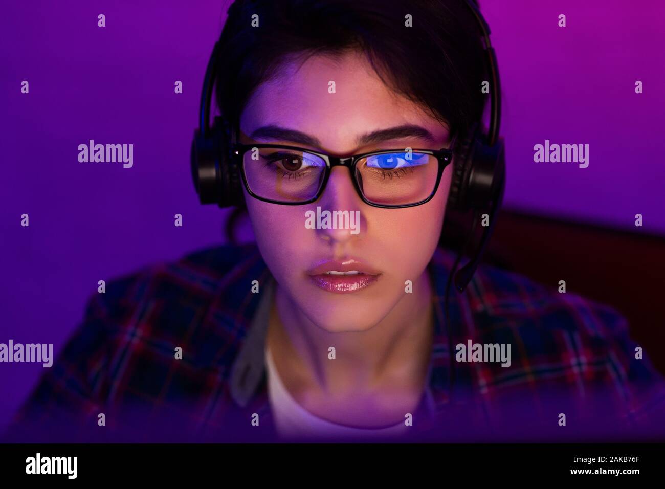 Female programmer working on laptop late at night. Room illuminated by ...