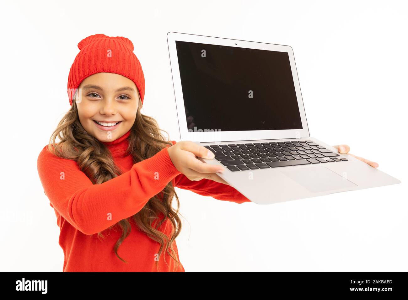 Happy caucasian girl in red hat and hoody shows a laptop isolated on ...