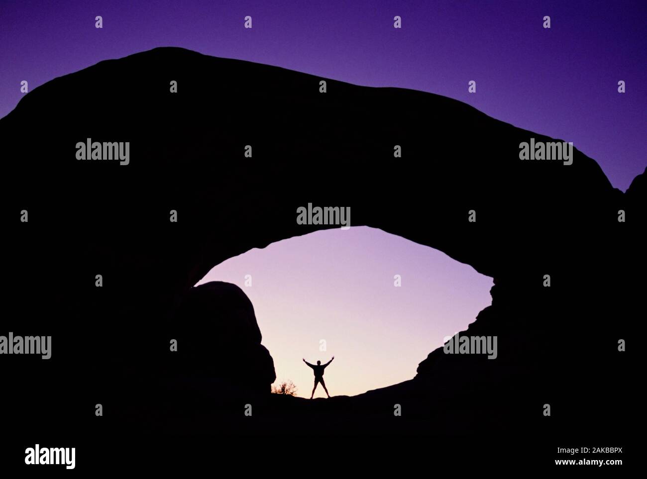 Silhouette of man standing under South Window Arch at sunset, Arches ...