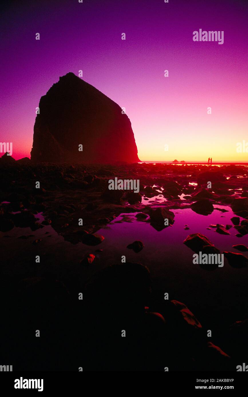 Landscape with silhouette of rock formation at Cannon Beach at sunset ...