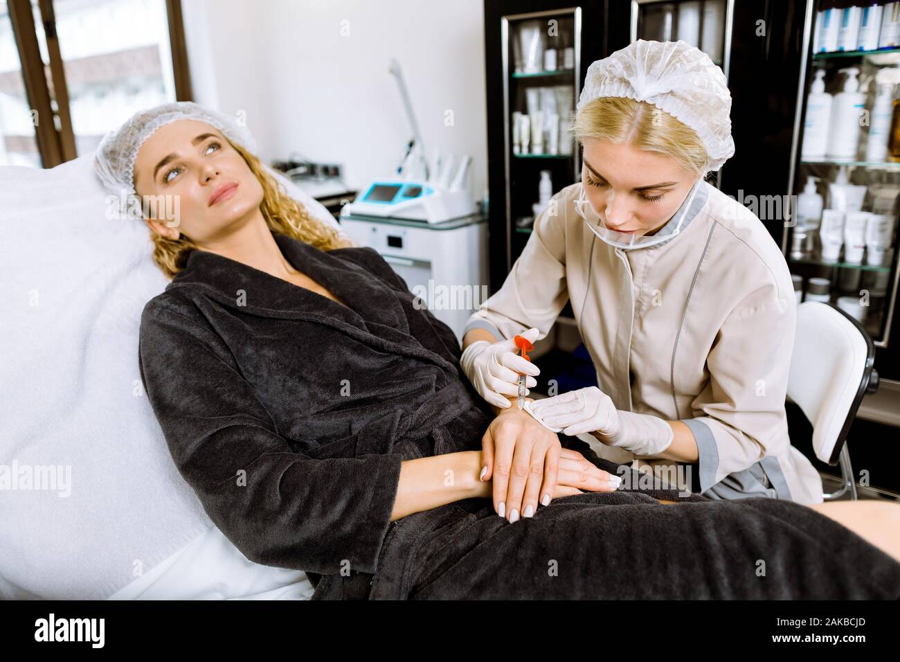 The doctor makes injections of botulinum toxin on the hands of a woman ...