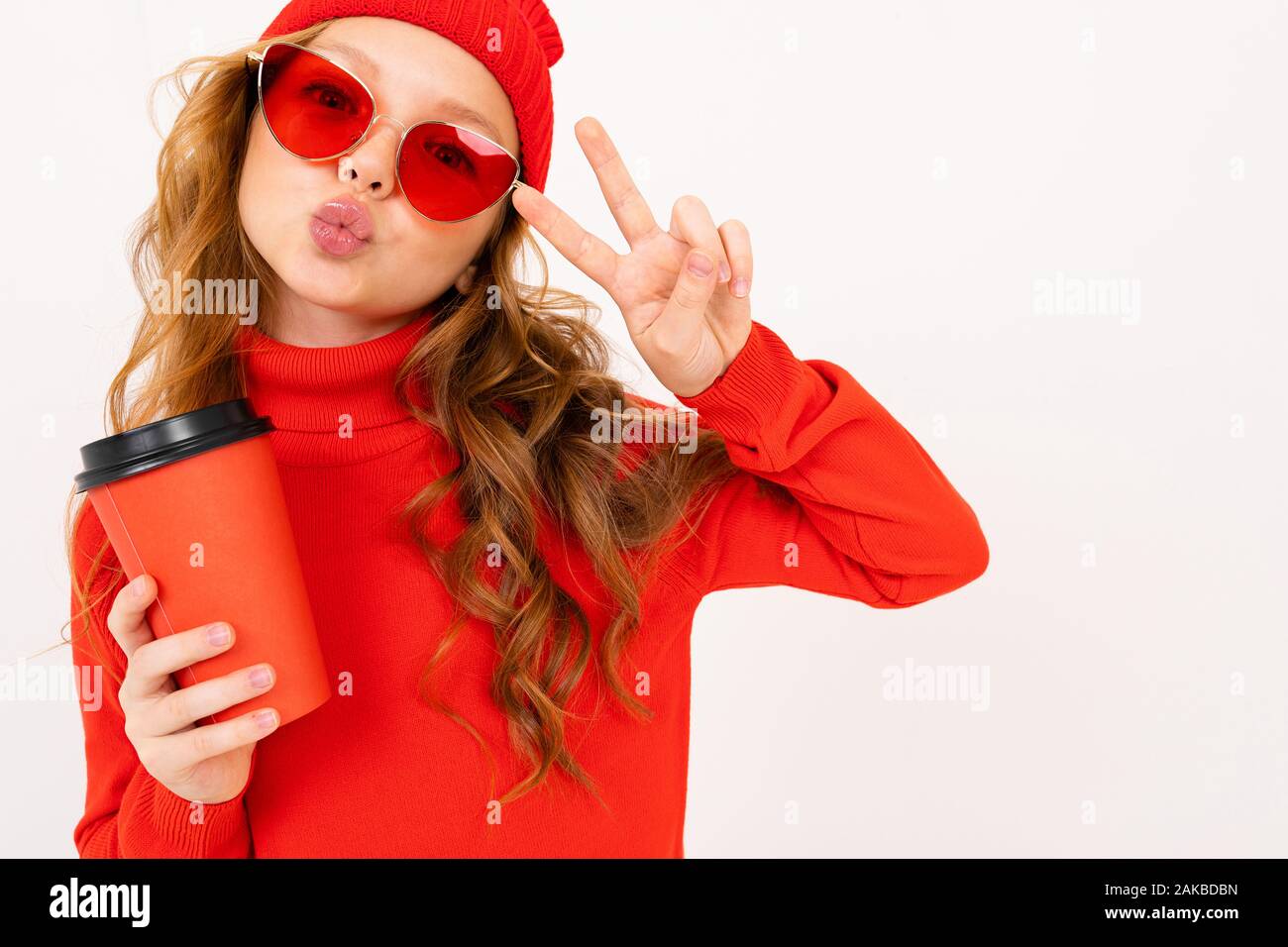 cute charming Caucasian girl in a red winter hat and sunglasses holds a ...