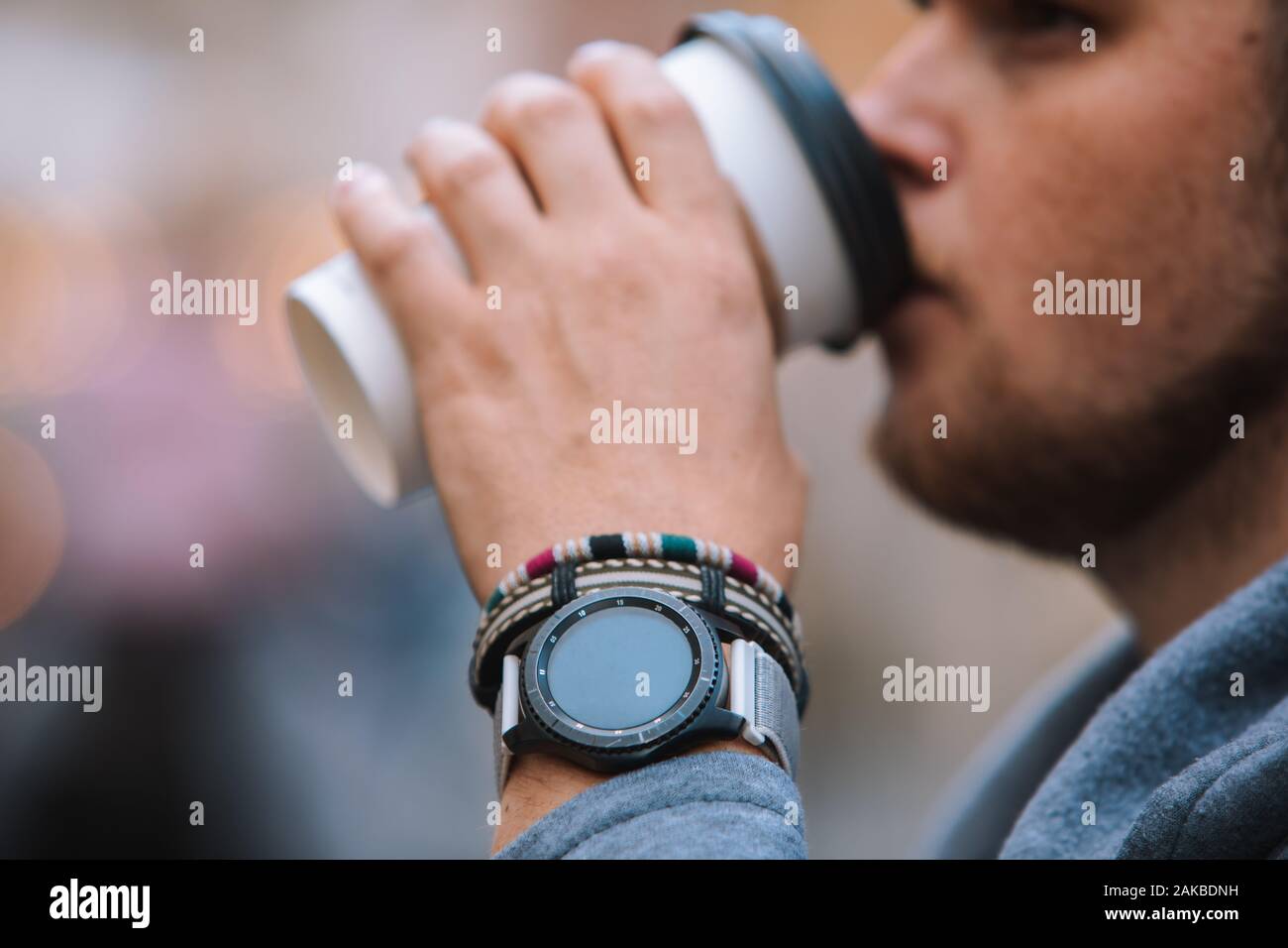 man drinking coffee from disposable cup smart watch with bracelet on ...