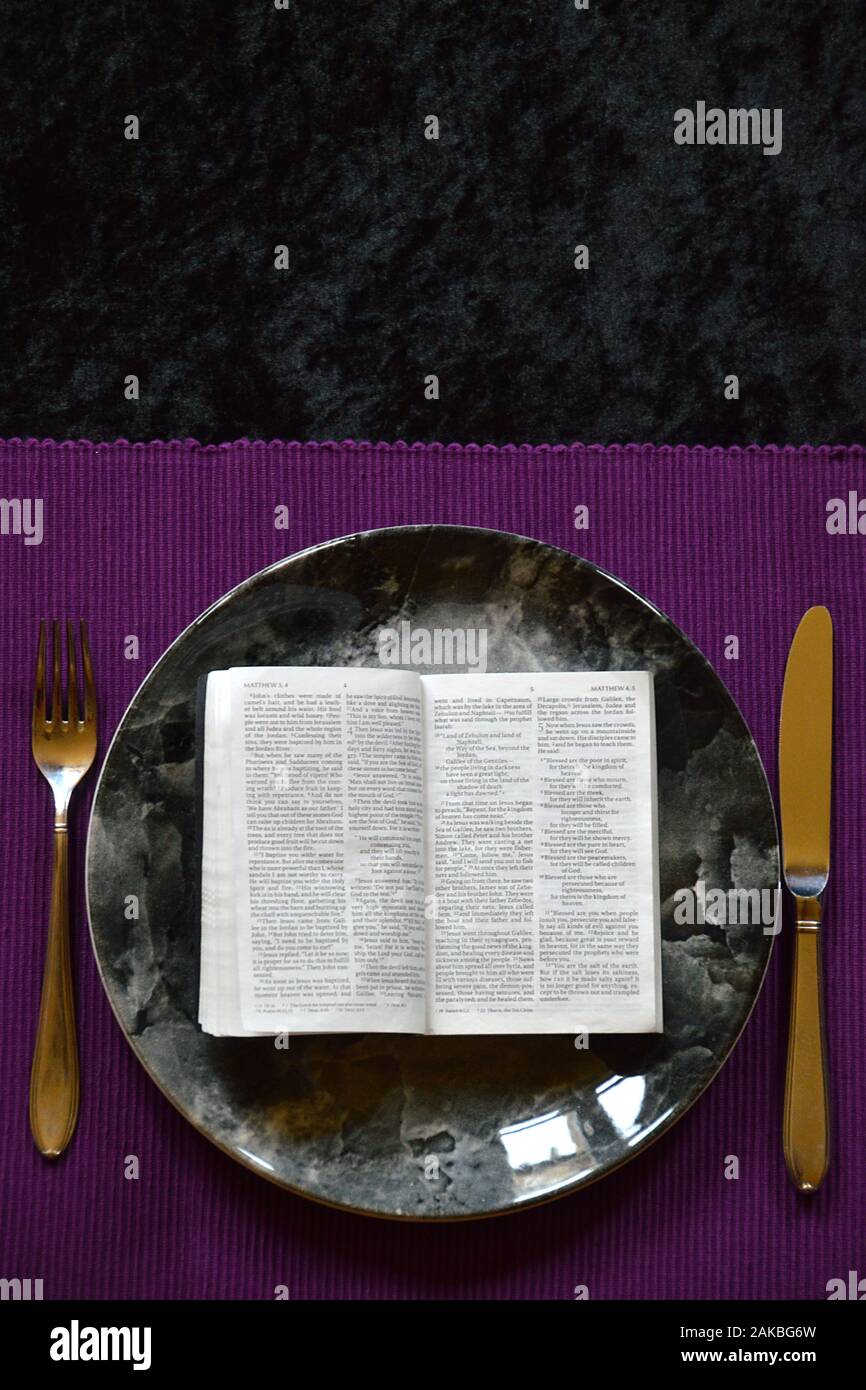 Bible opened up at Matthew 4:4 on a dinner plate on a purple placemat ...