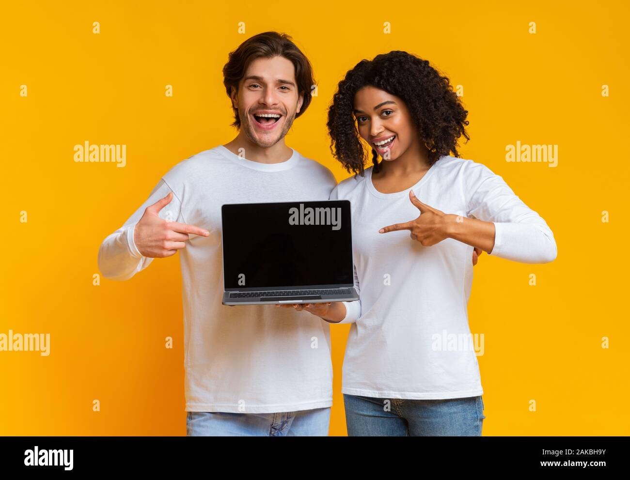 Cool website. Smiling multiracial couple holding laptop with black ...