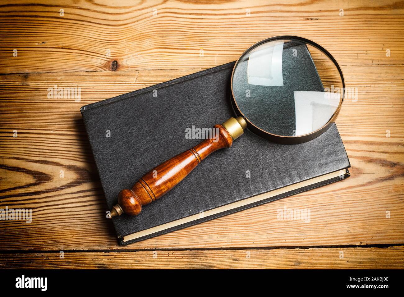 Magnifying glass on a book and on a rustic wooden table Stock Photo - Alamy