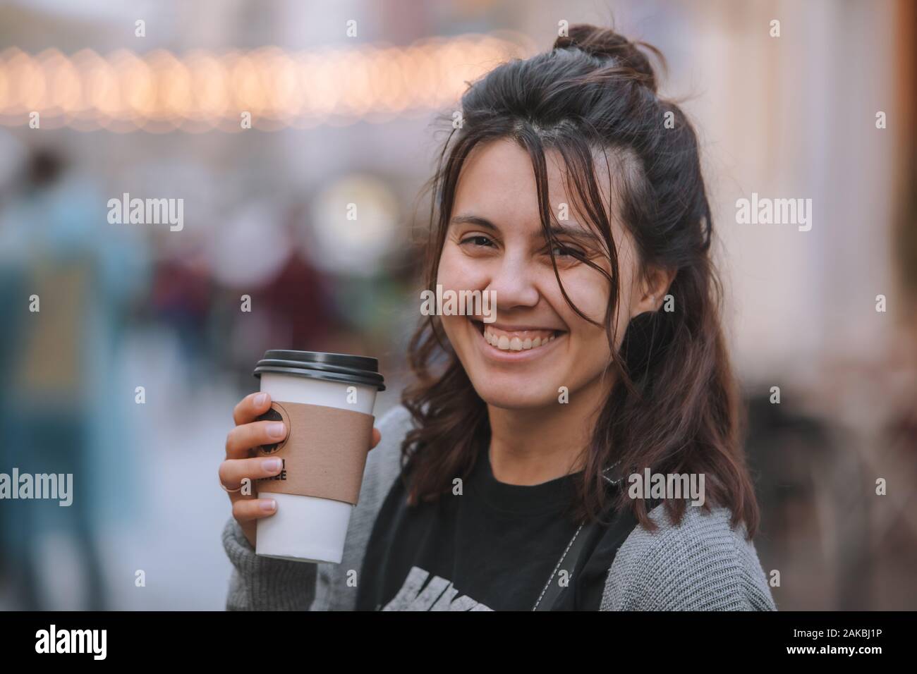 young pretty woman at city street drinking coffee from disposable cup ...