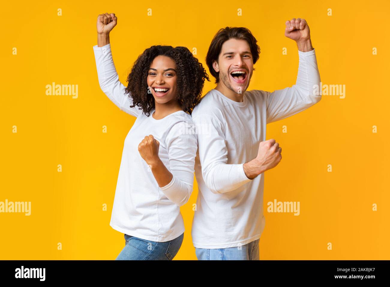 We made it. Joyful multiracial couple celebrating success, raising ...