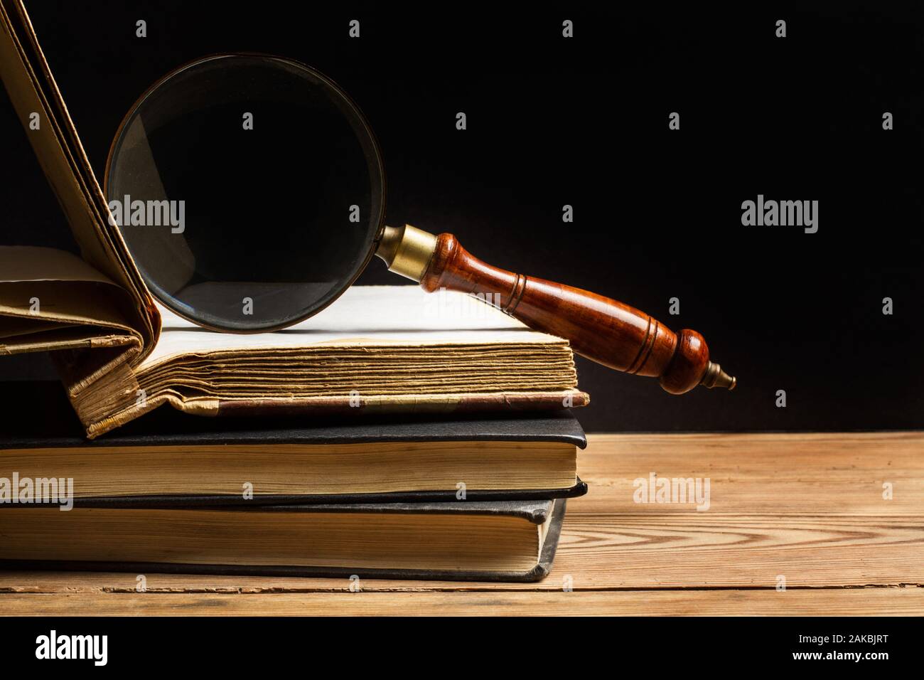 Magnifying glass on a book and on a rustic wooden table Stock Photo - Alamy