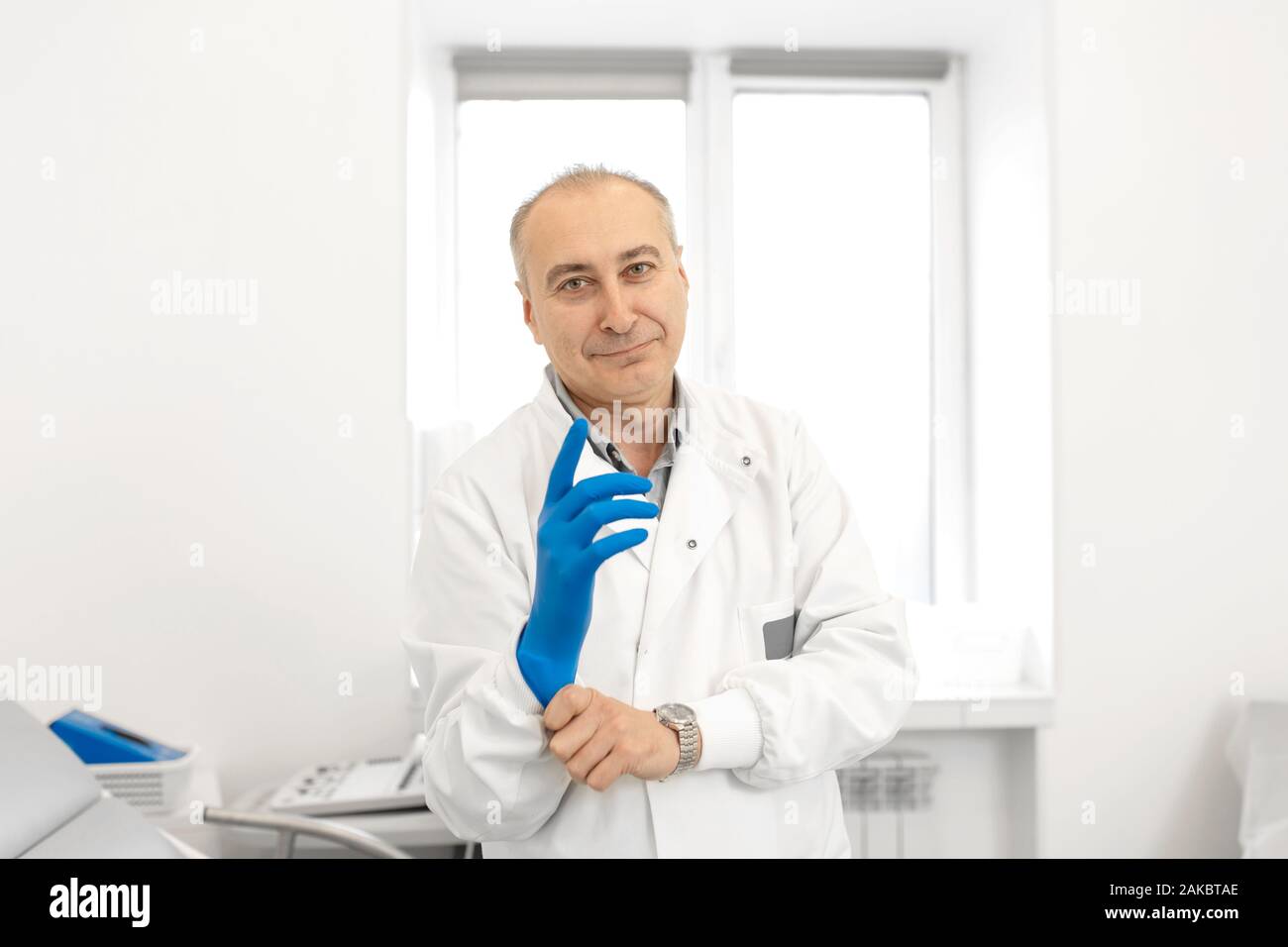 Portrait of a urologist doctor putting on medical gloves before ...