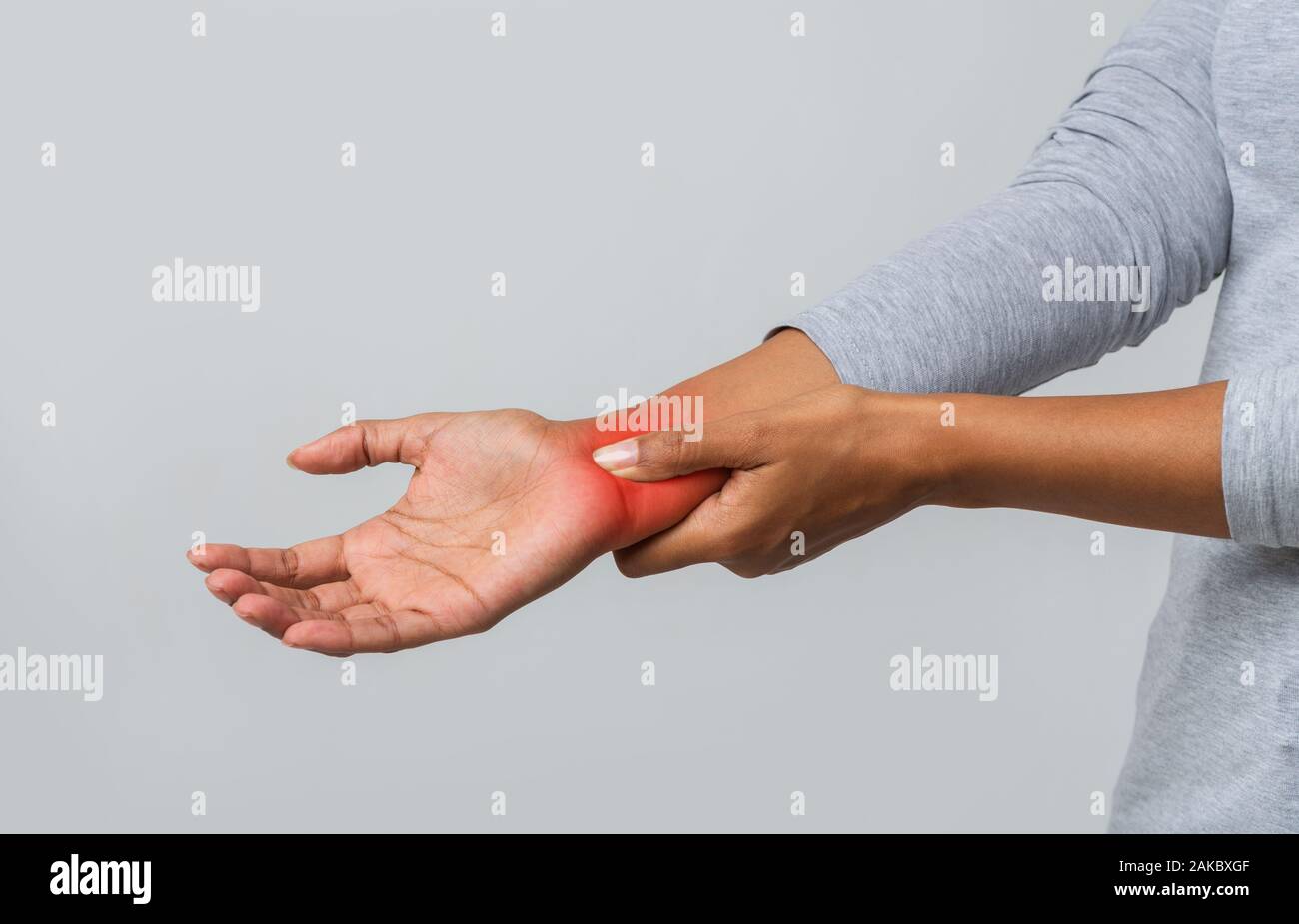 Female inflamed highlighted with red wrist over grey studio background ...