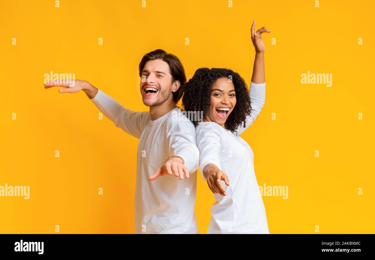 Lets party. Joyful multiracial couple dancing back to back, having fun ...