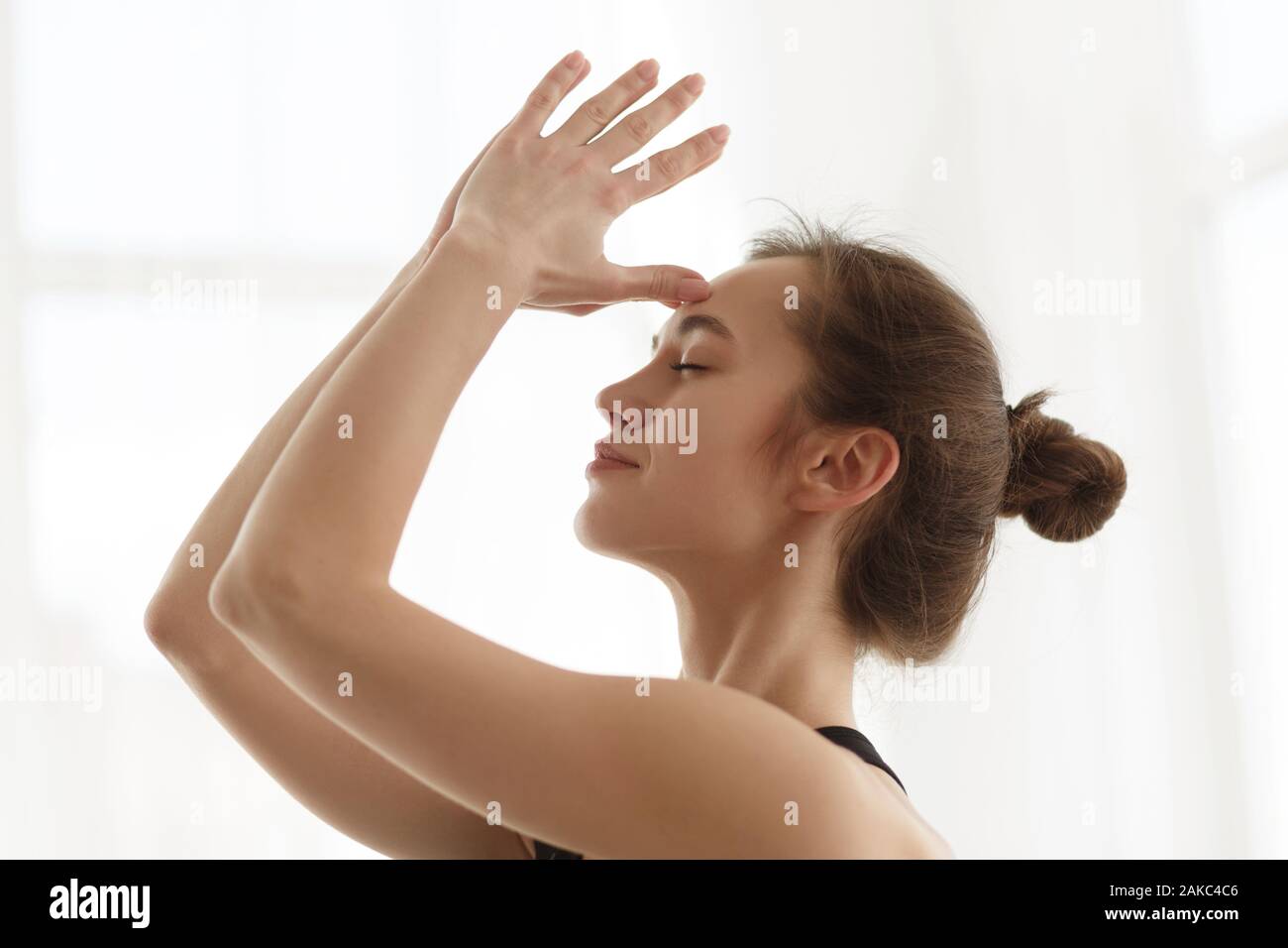 Girl doing meditating exercise with hands together on forehead over ...