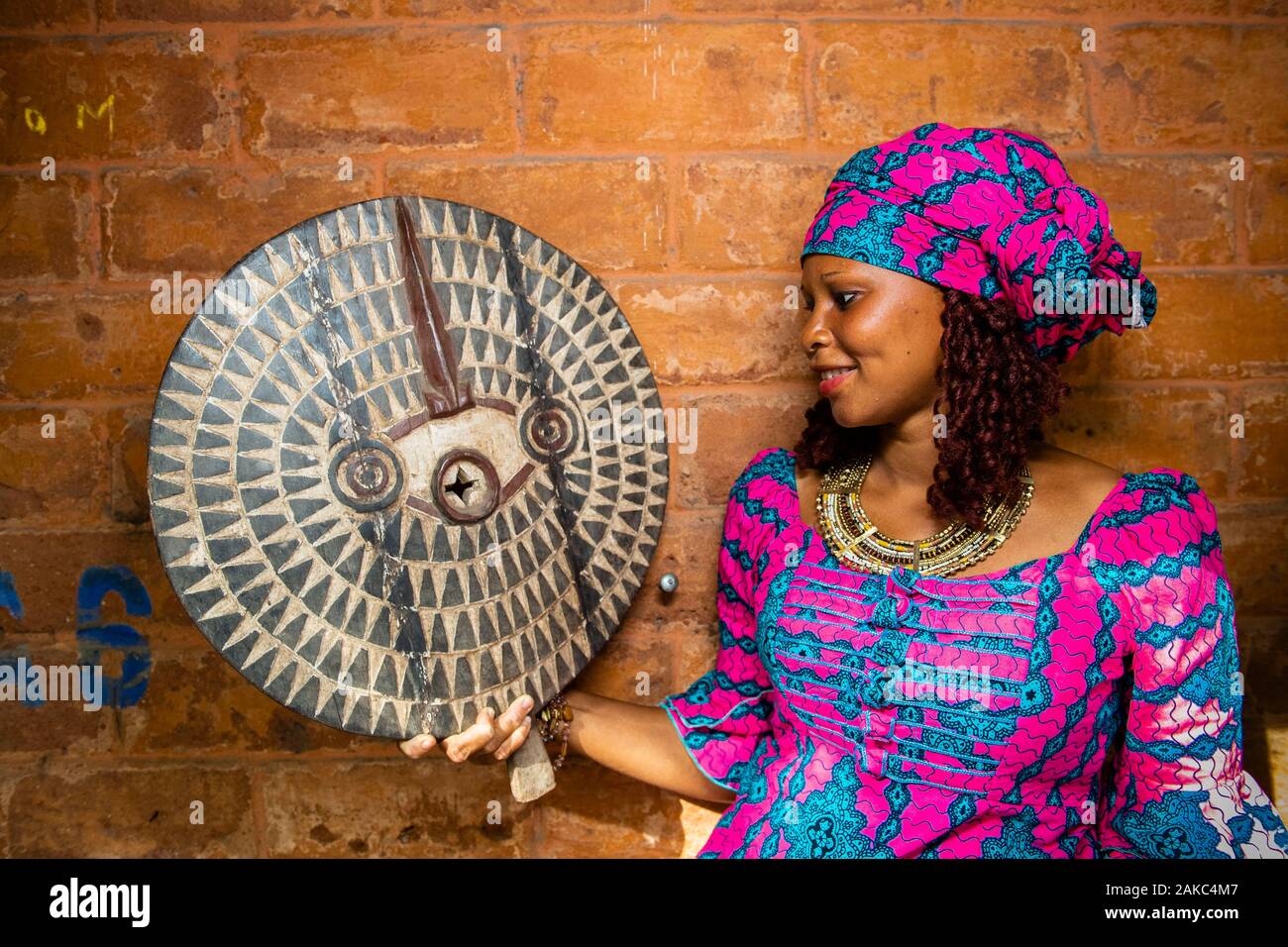 Benin, Cotonou, woman wearing traditional clothes holding handcraft ...