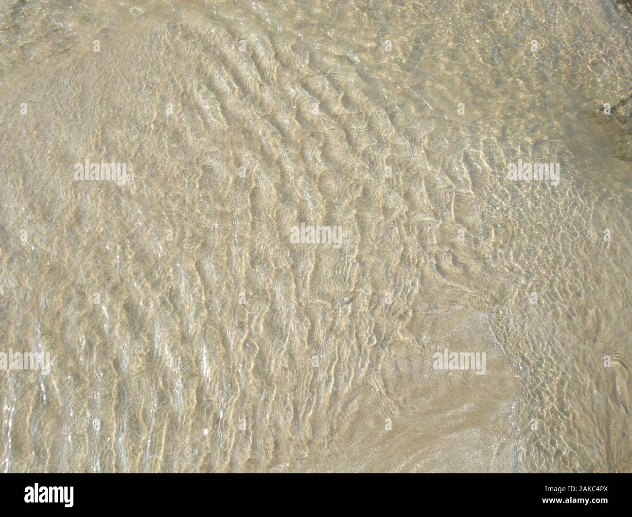 Water flowing over sand forming pattern Stock Photo - Alamy