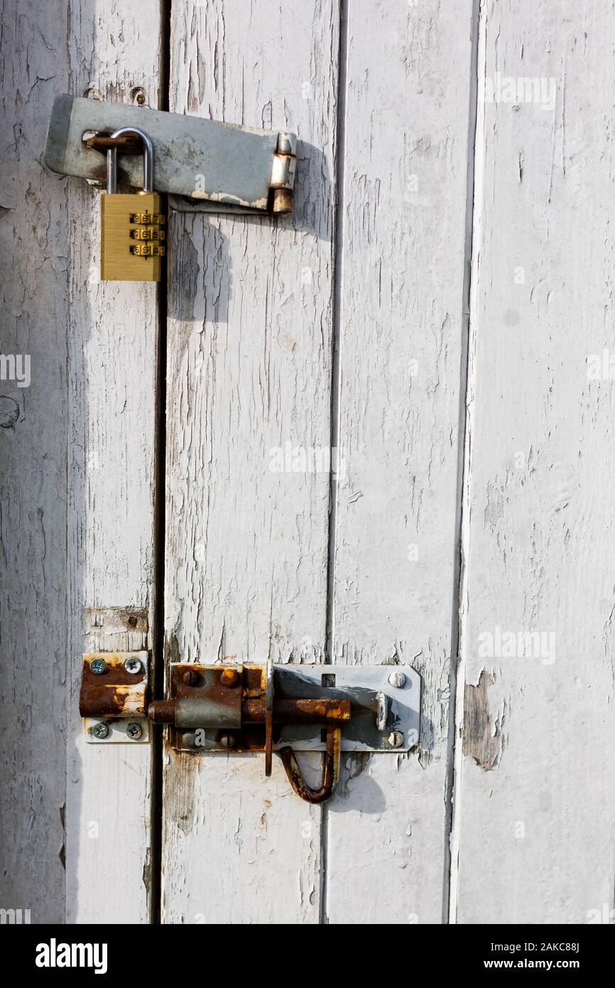 An old wooden door secured by a padlock and deadbolt to stop anyone ...