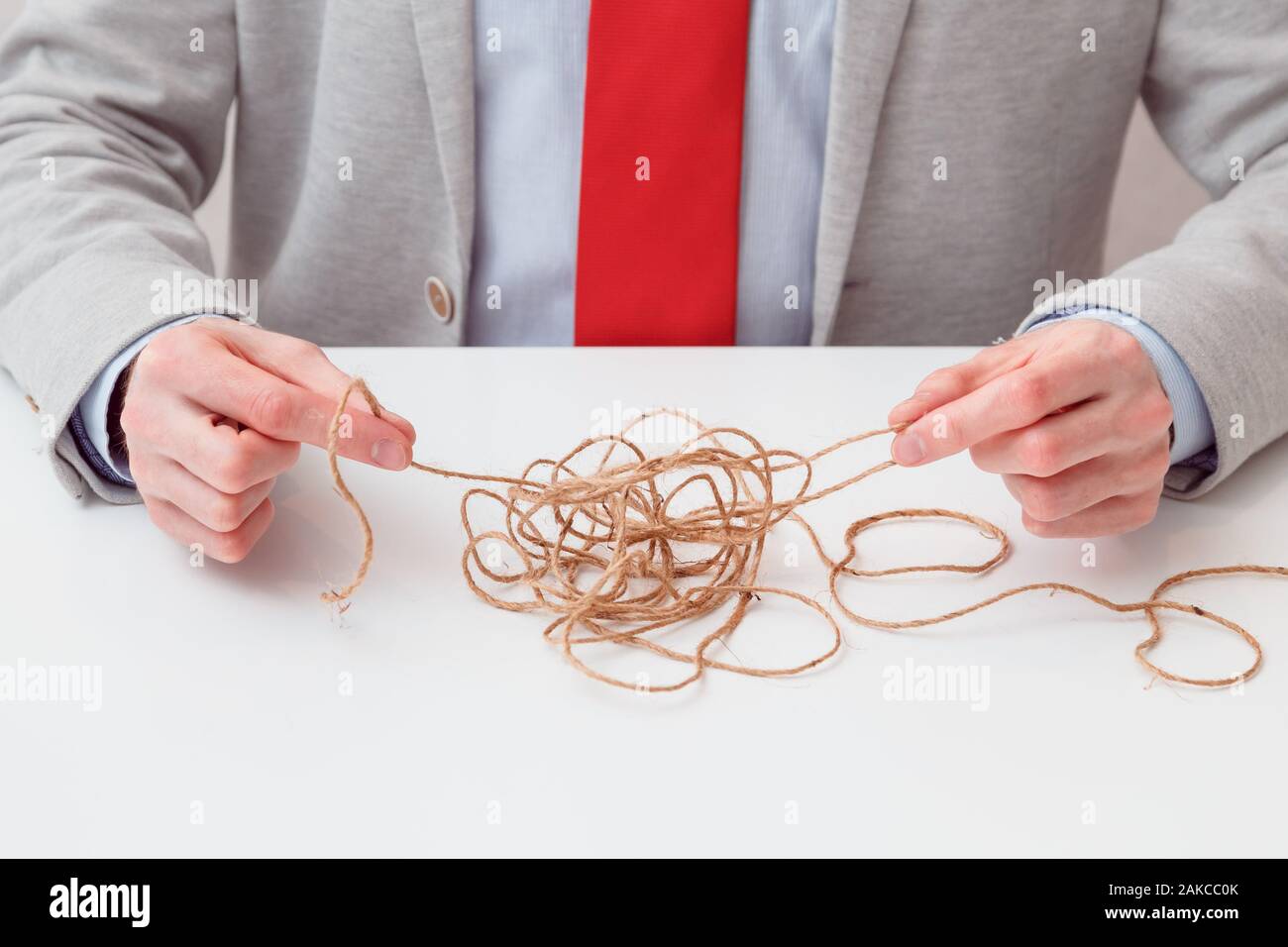 Alone businessman try to unwinds tangled thread ball like puzzle out ...