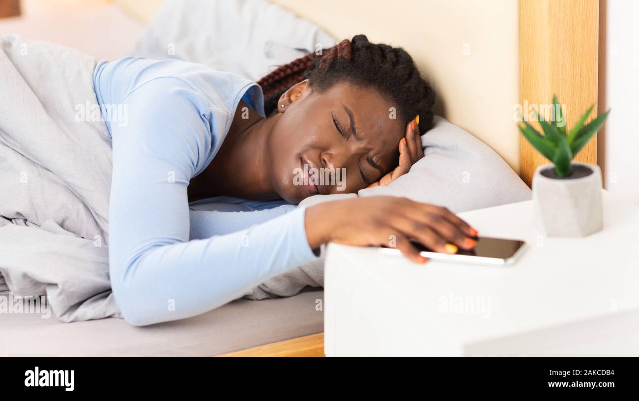 Black Woman Turning Off Alarm-Clock On Phone Heaving Headache Lying In ...