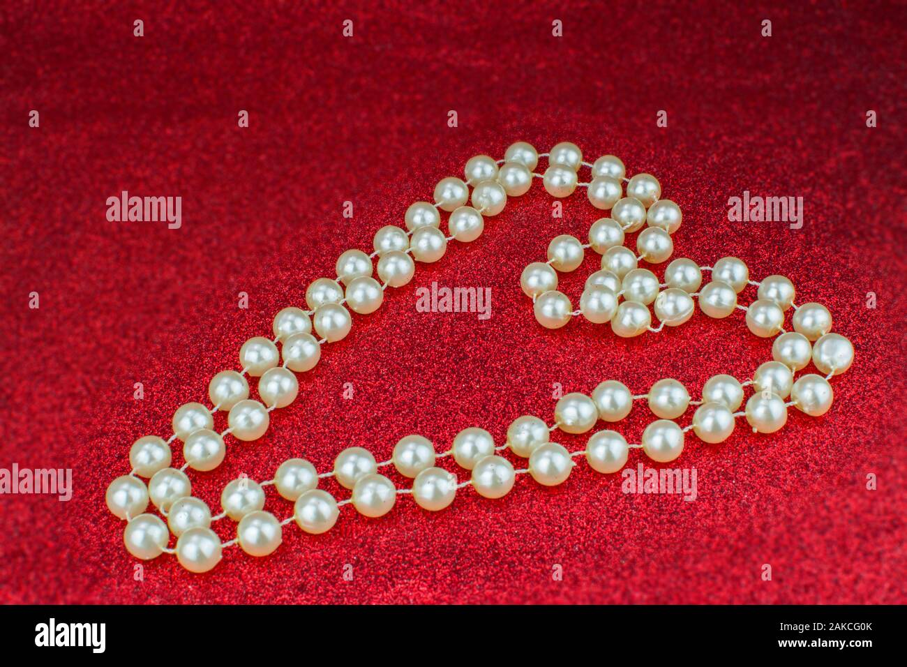 string of pearl on red sparkly background Stock Photo - Alamy