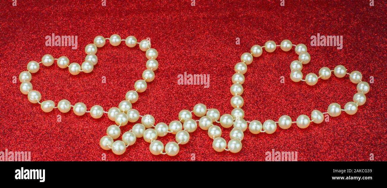 string of pearl on red sparkly background Stock Photo - Alamy