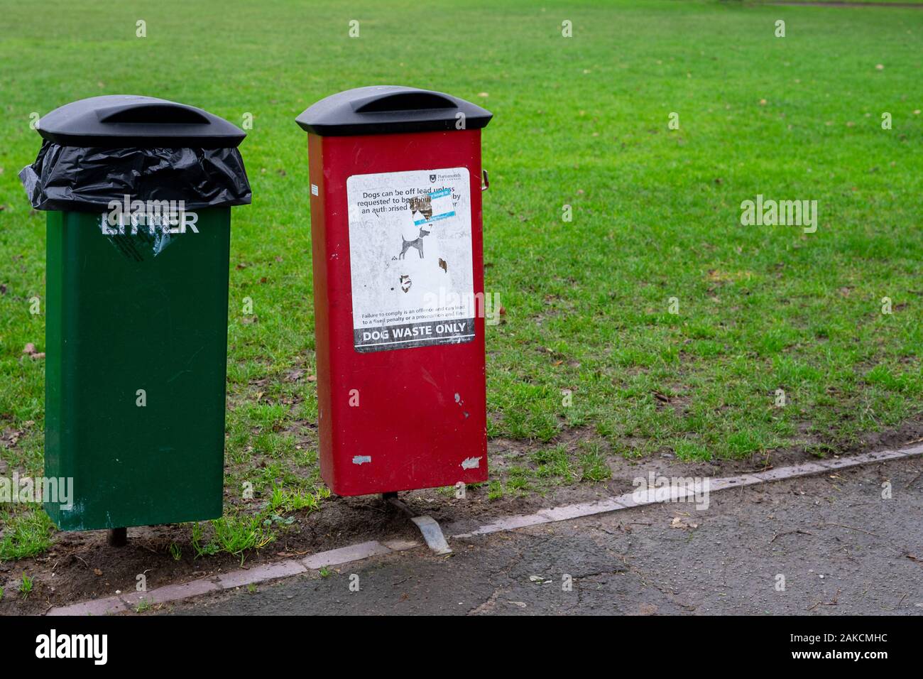 A green litter bin next to a red dog waste bin in a park Stock Photo ...