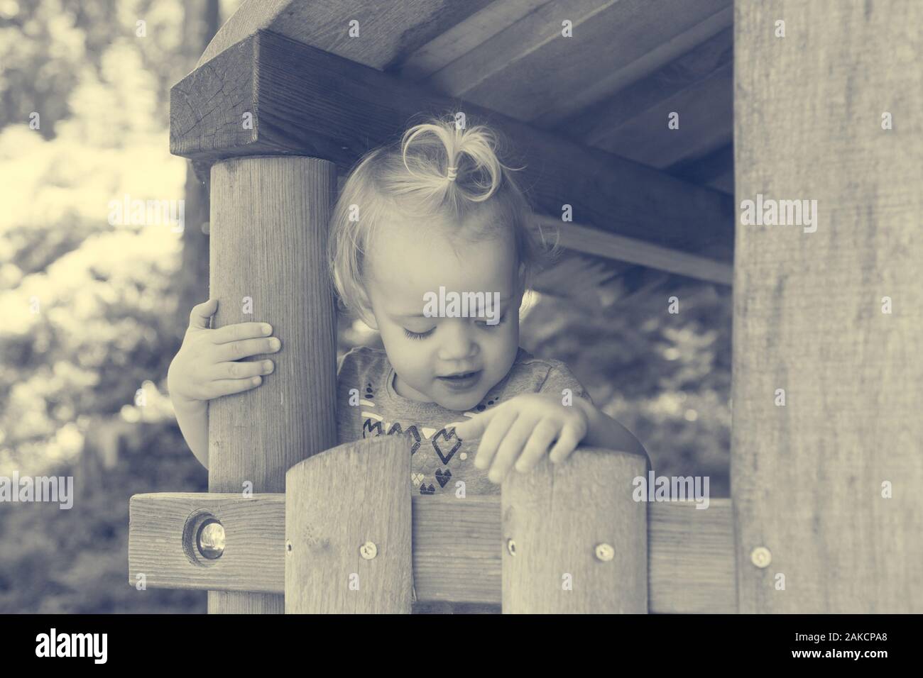 Cute blonde girl playing in wooden house looking through window Stock ...