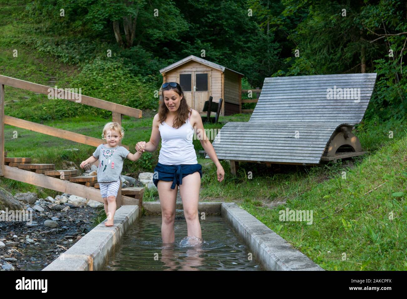 Mother and daughter having fun walking through water tank at outdoor ...