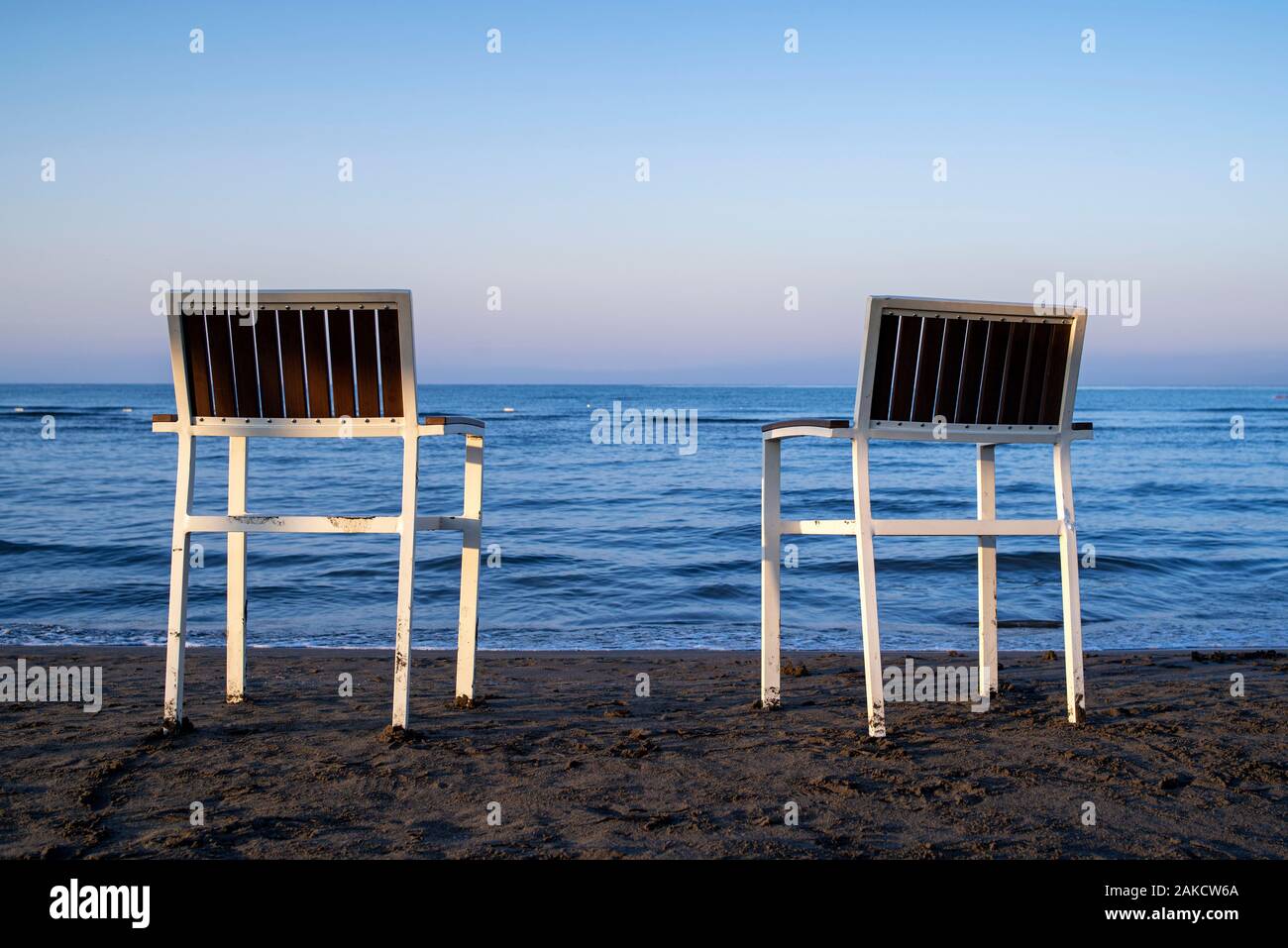 Chairs stand in the sand.Two empty chairs stand on beach in evening ...