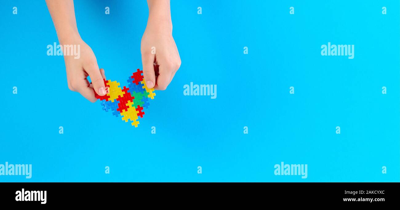 Child hand holding colorful heart on light blue background. World ...