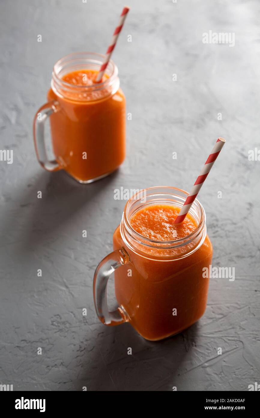 Homemade Mango Carrot Smoothie in glass jar mugs over gray background ...