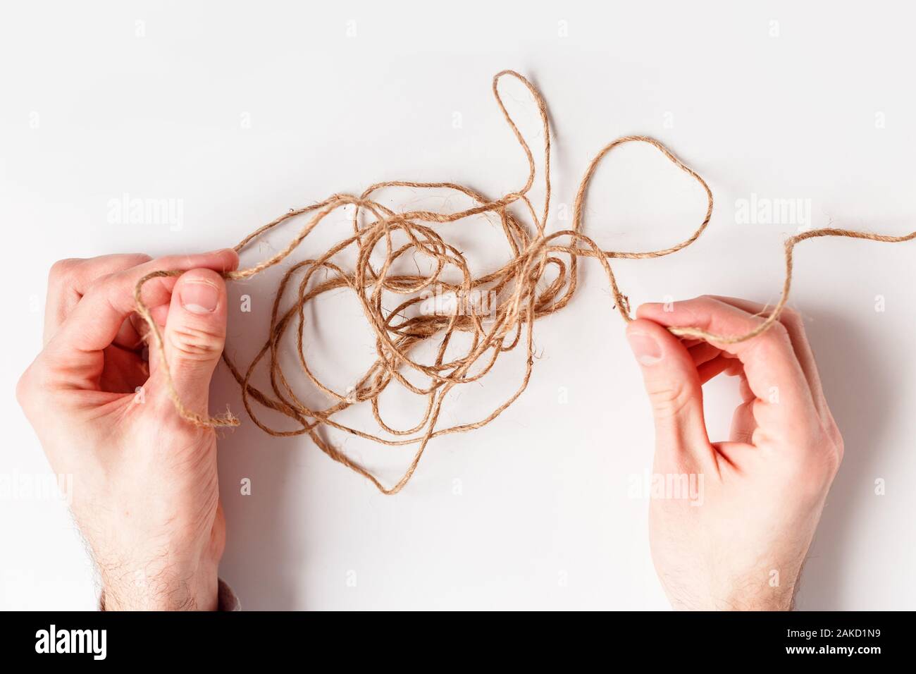 Man untangles a tangled thread. Top view isolated on a white background ...
