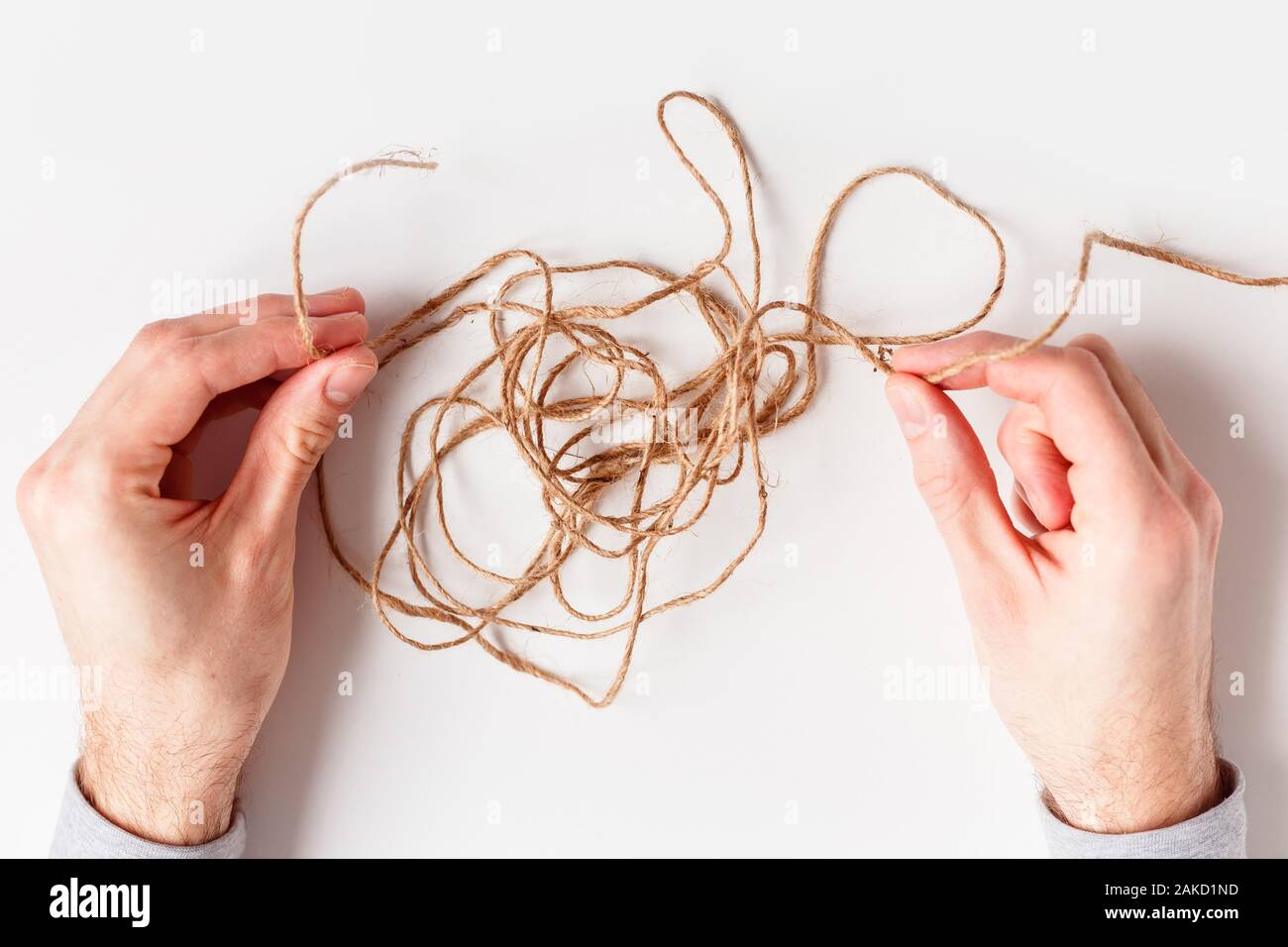 Man untangles a tangled thread. Top view isolated on a white background ...