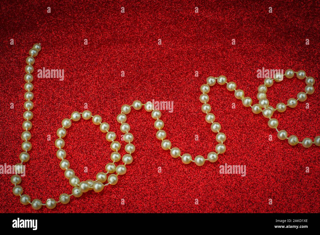 string of pearl on red sparkly background Stock Photo - Alamy