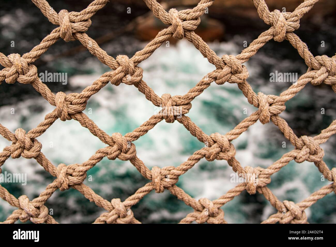 Background from a strong rope on a background of blue water.Close-up of ...