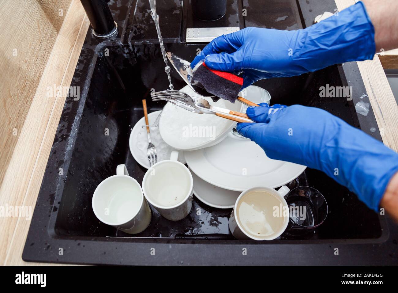 Washing of the dishes - man hands in gloves washing with sponge and ...