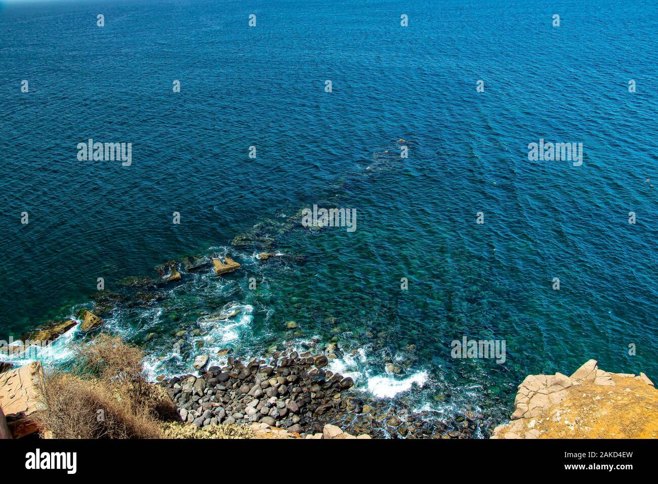 Sea cliff with black stones on Goree island, near Dakar, Senegal. There ...
