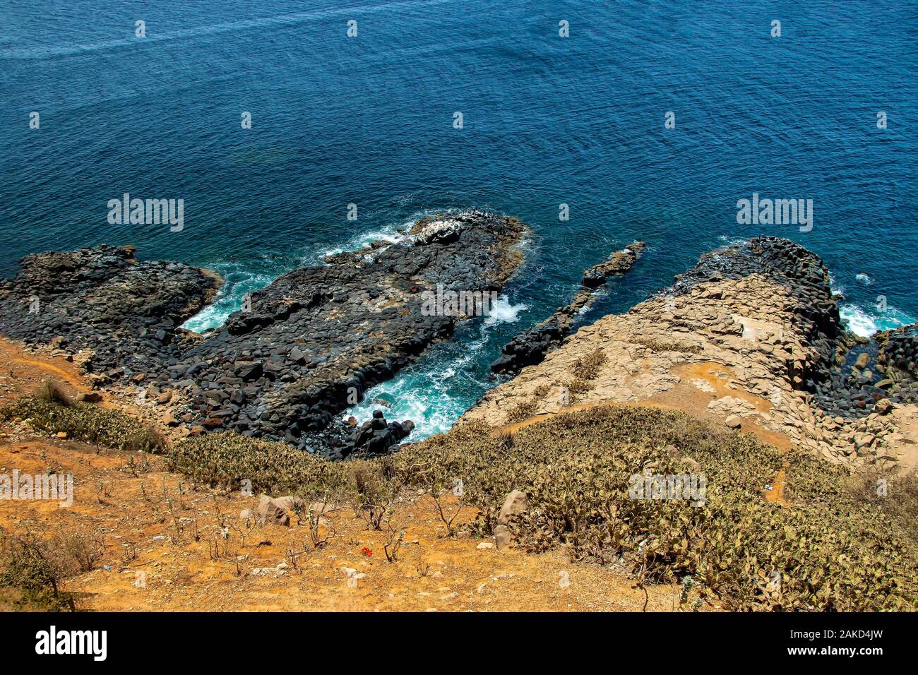 Sea cliff with black stones on Goree island, near Dakar, Senegal. There ...