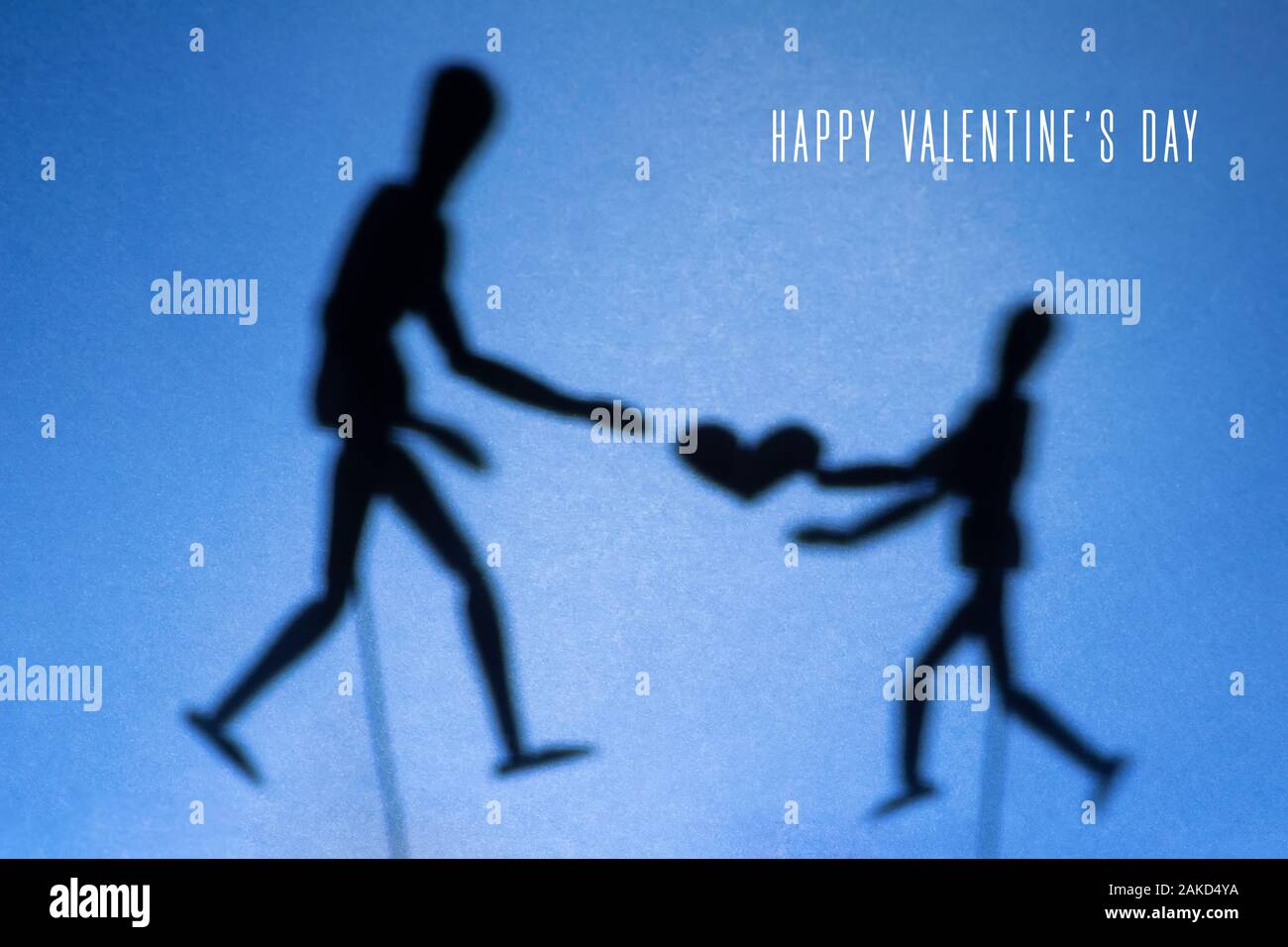 Two shadows of puppets run towards each other. One figurine stretches ...