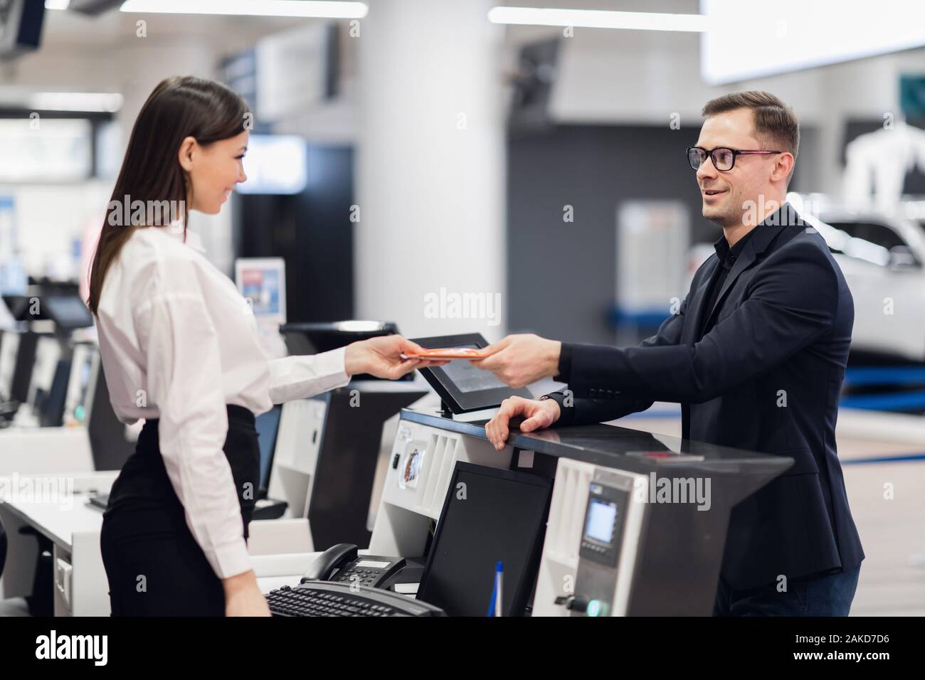Friendly woman staff taking passport from passenger at airport check in ...
